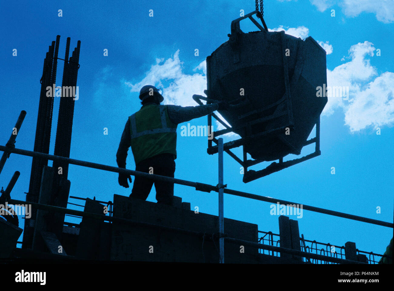 Construction worker on site guiding a cement bucket Stock Photo - Alamy