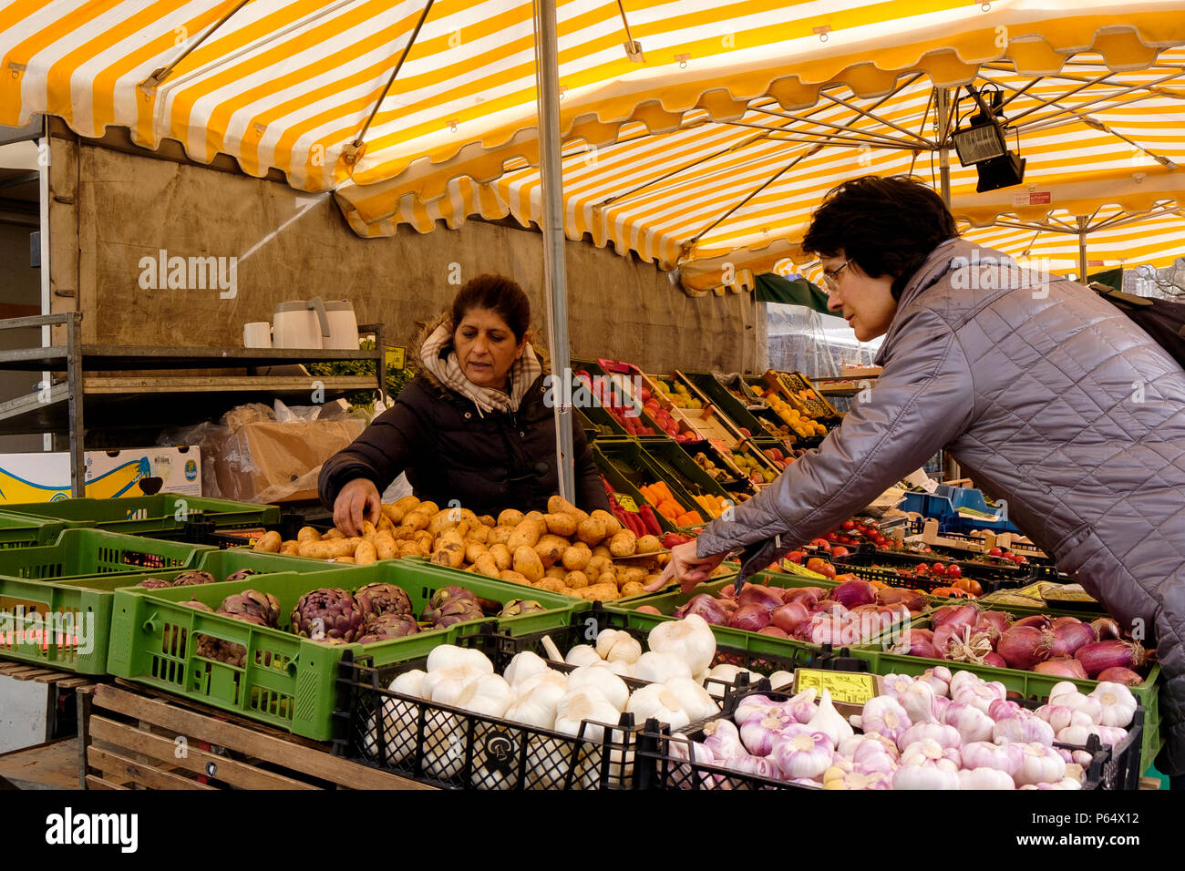 A customer buying fresh vegetables at an outdoor market stall in ...