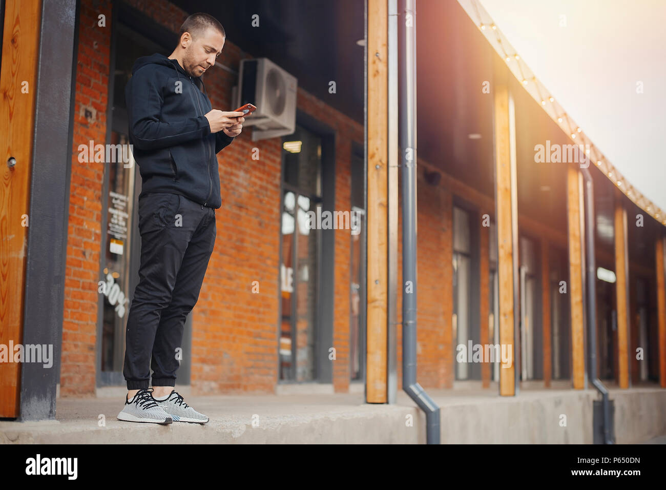Bearded man standing next to red bricked building and staring at the ...