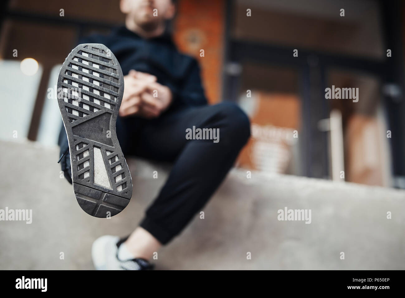 Bearded man sitting on concrete step and lifting leg Stock Photo - Alamy