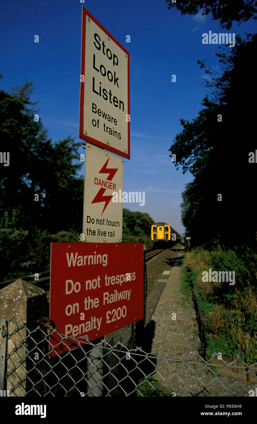 Warning signs at a foot crossing near Basingstoke, Hampshire as a train ...