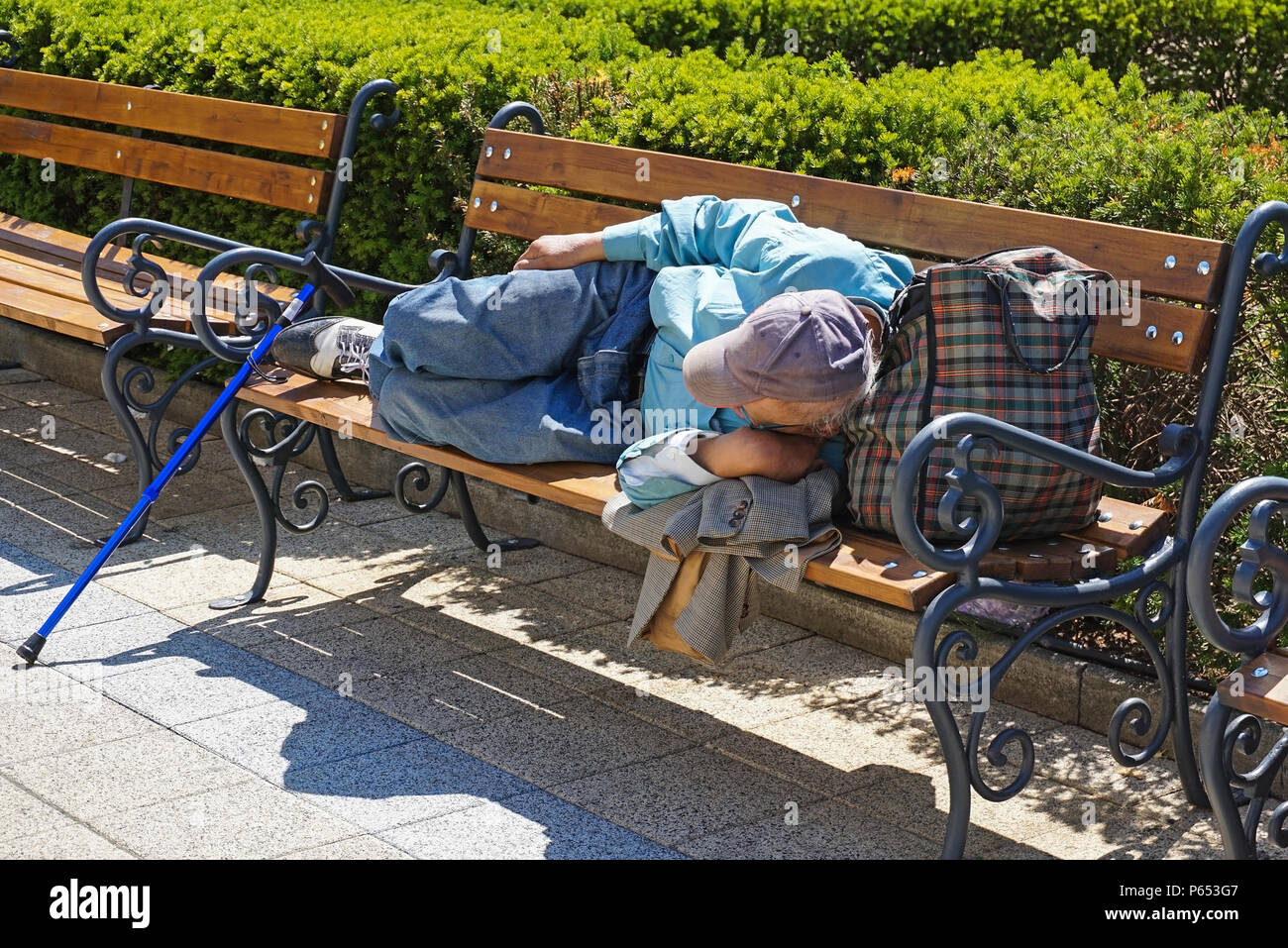Homeless man is sleeping on a park bench outdoor Stock Photo - Alamy