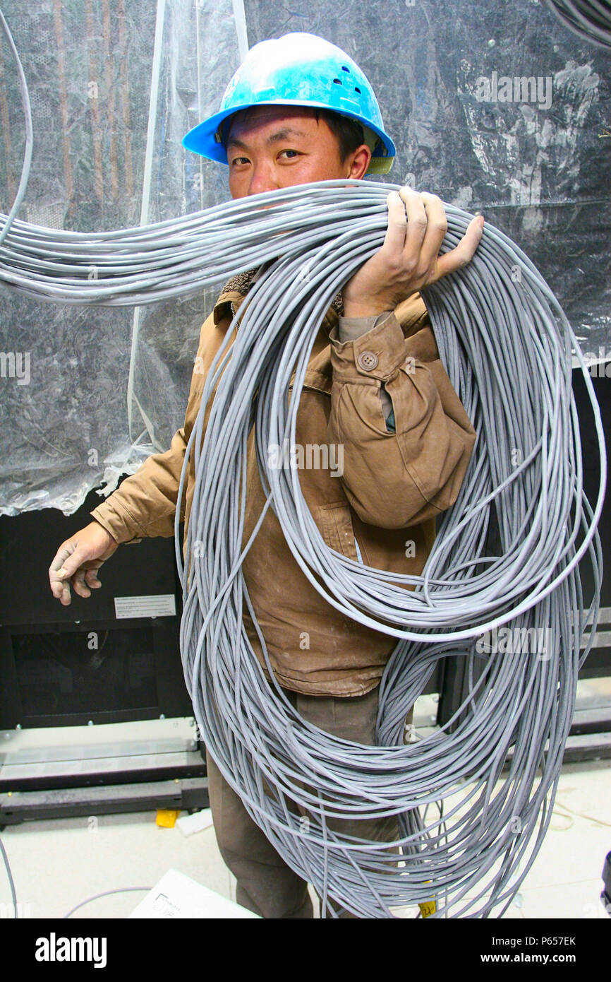 A Chinese construction workers carries wire cable during the fitting ...
