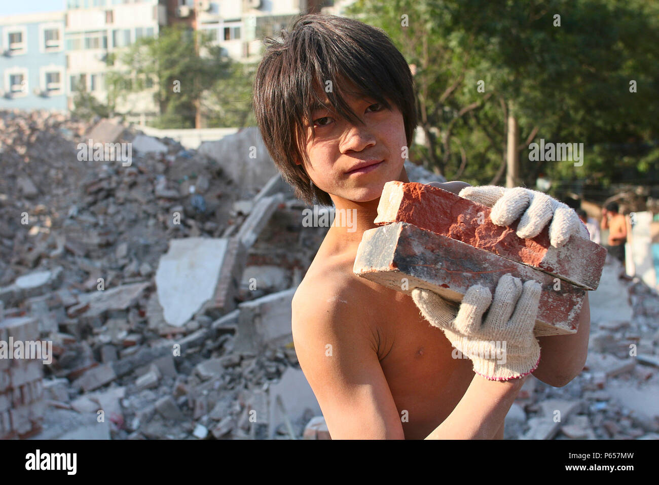 A young migrant labour collecting used bricks during the demolition of ...