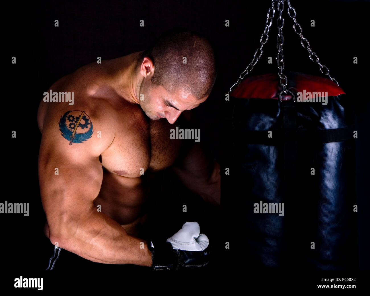 Attractive athletic young man training kickboxing using black punching ...