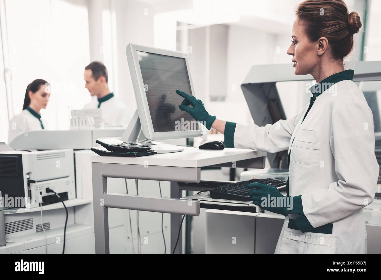Waist up of concentrated laboratory assistant working with computer ...