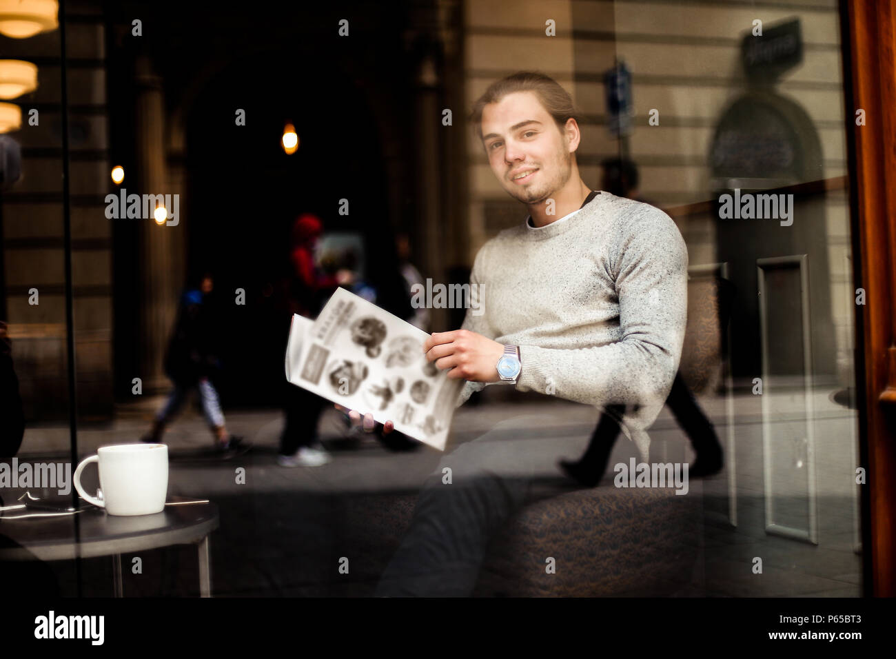 Young male person reading menu at cafe with cup of coffee on table ...