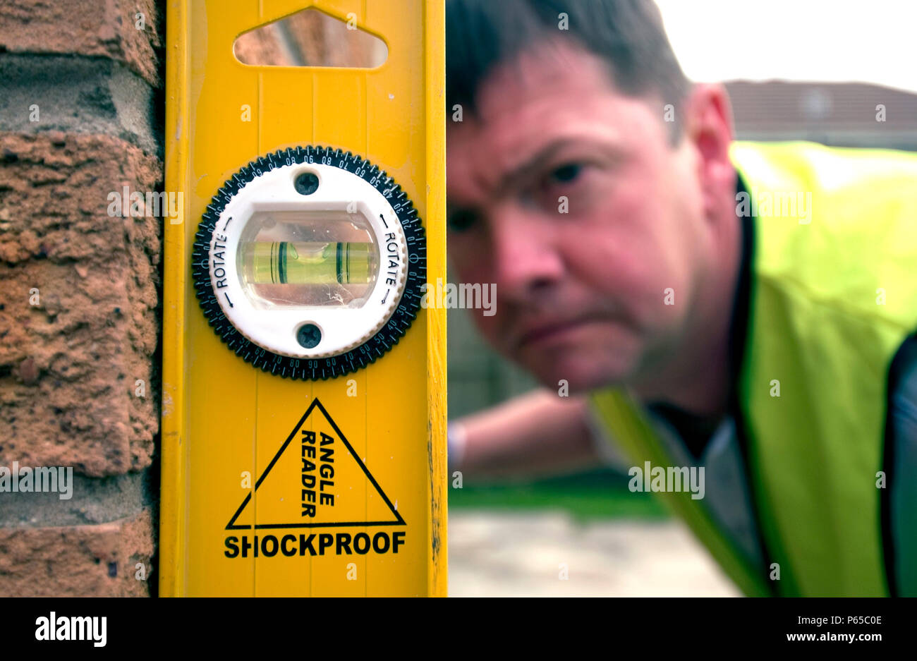 Builder using a spirit level Stock Photo - Alamy