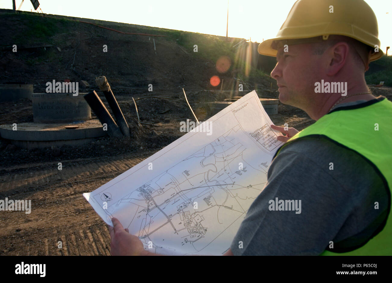 Building technician checking plan on site Stock Photo - Alamy