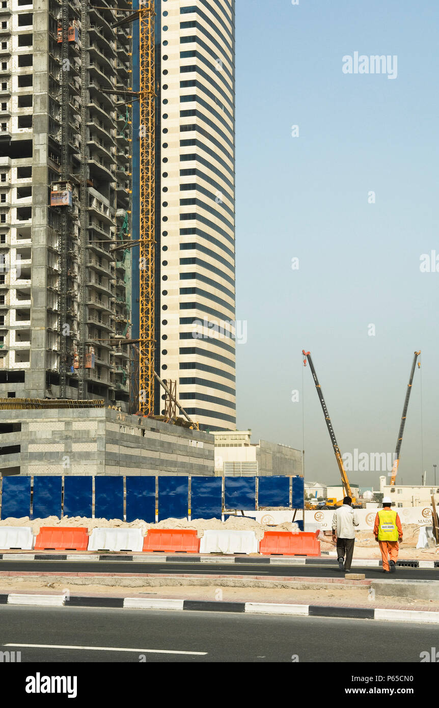 Construction workers cross towards a construction site next to tower ...