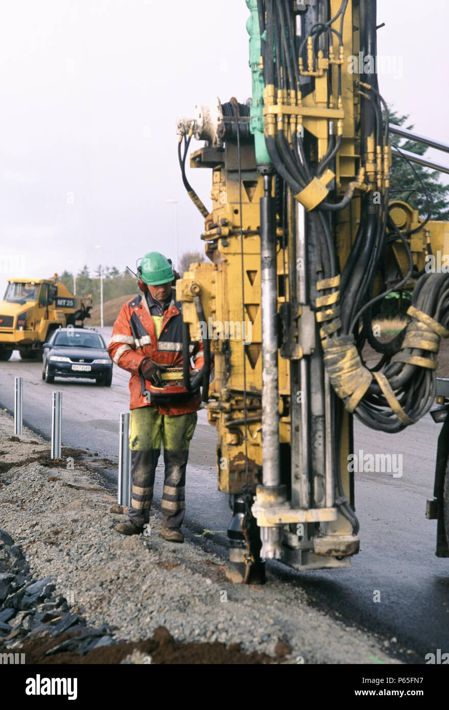 Safety barrier posts are fitted along the road side using a lorry ...
