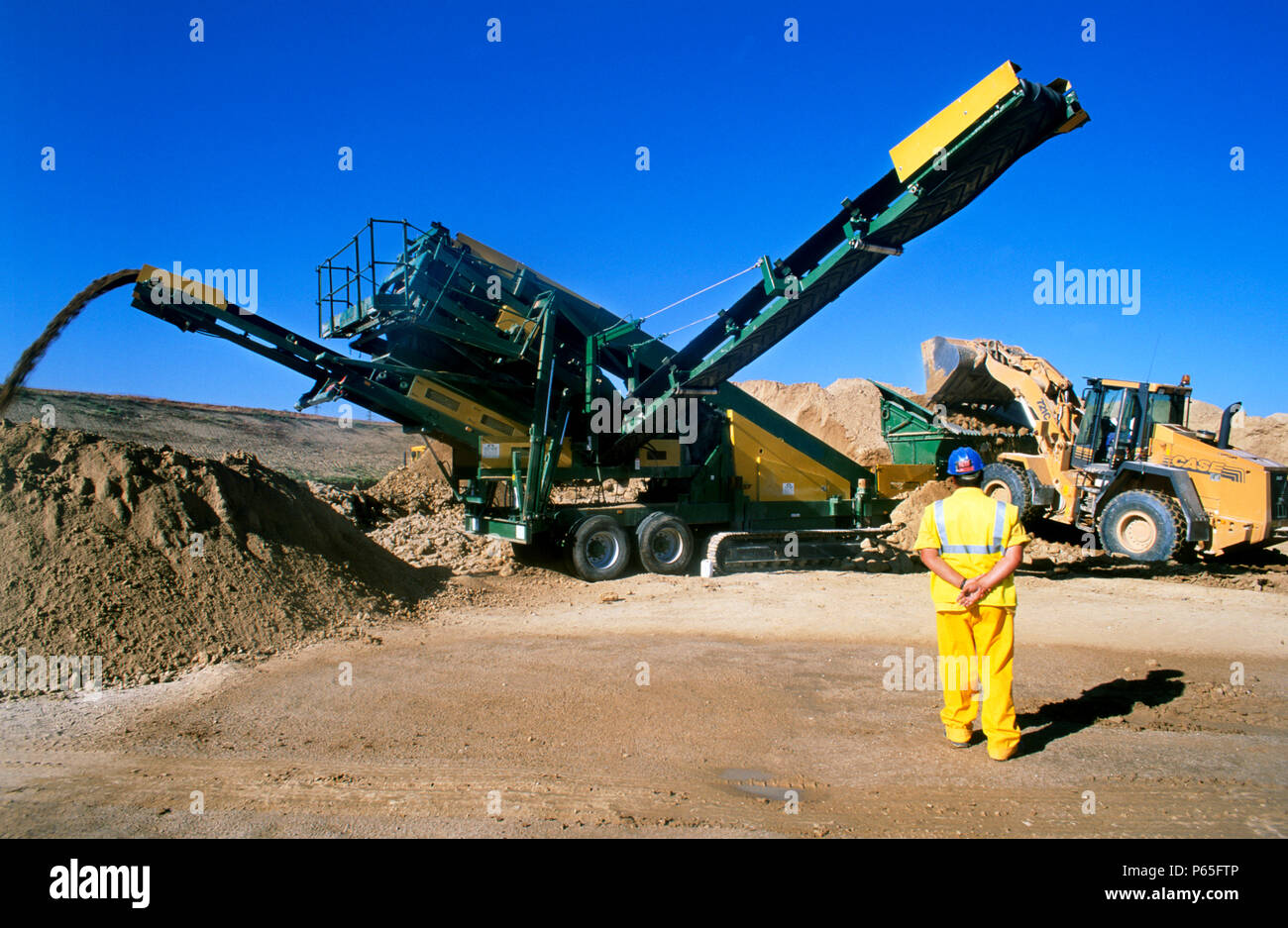 A wheeled loader loads aggregate onto conveyors in an aggregate yard ...