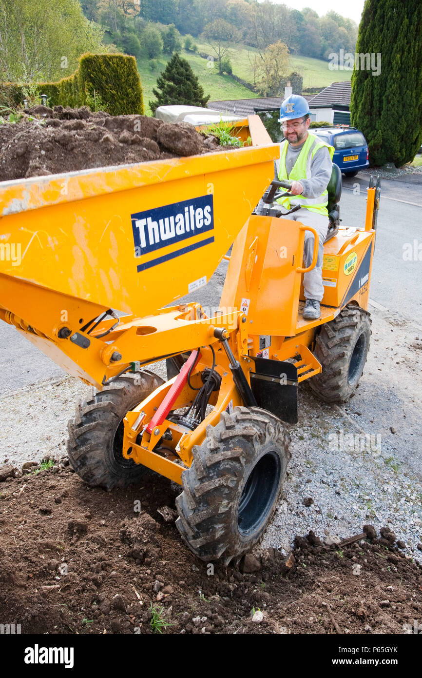 A builder driving a mini dumper truck on a house extension, building ...