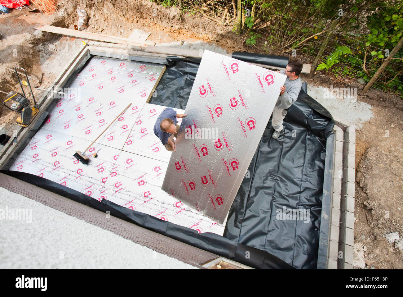 Builders lay under floor insulation into a house extension in Ambleside ...