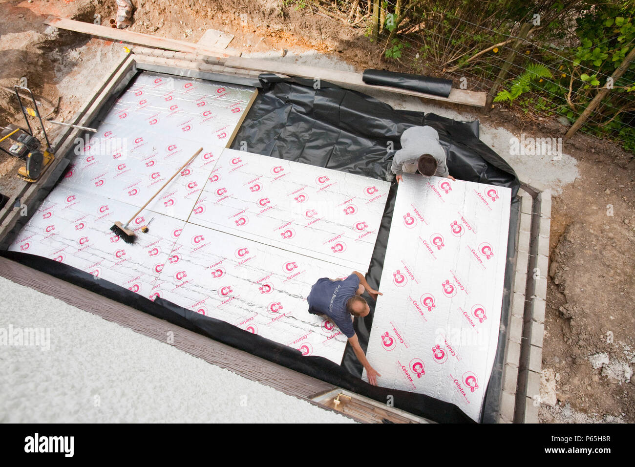 Builders lay under floor insulation into a house extension in Ambleside ...