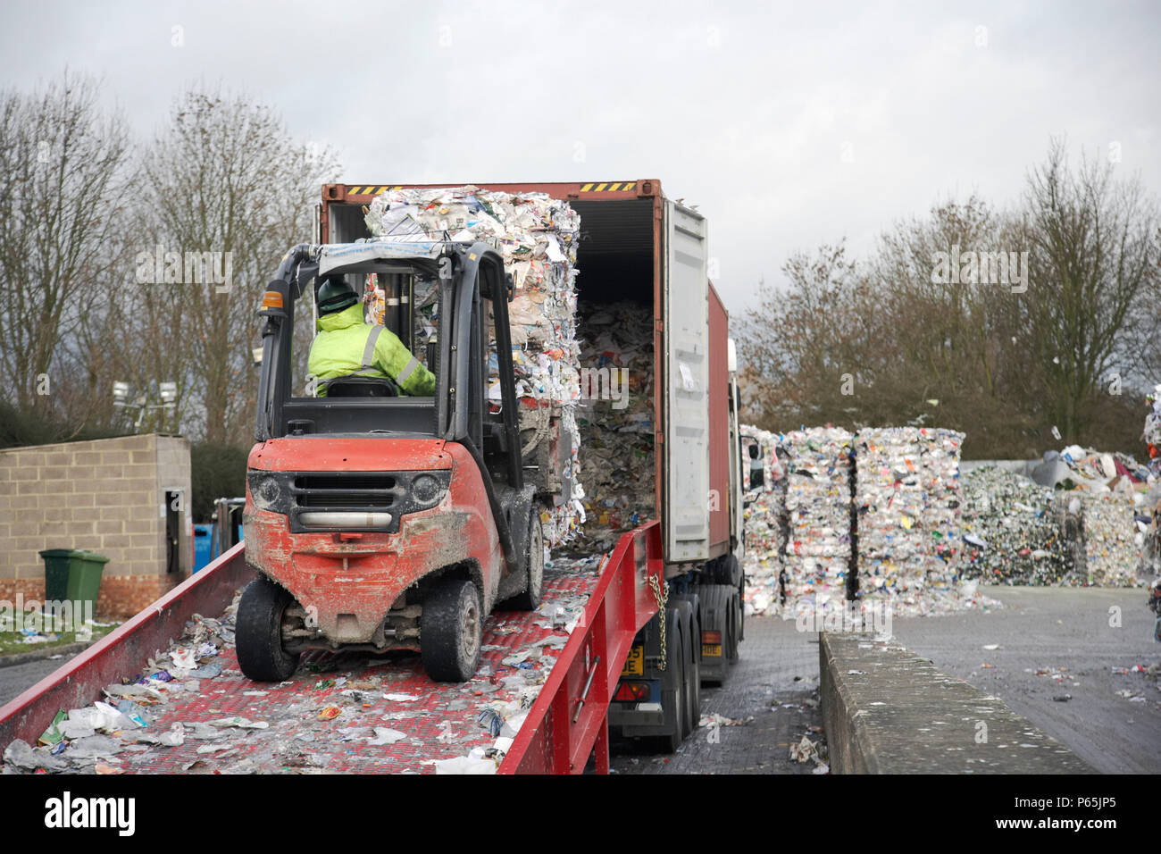 Grip lift truck loading compacted paper recycling bundles on to lorry ...