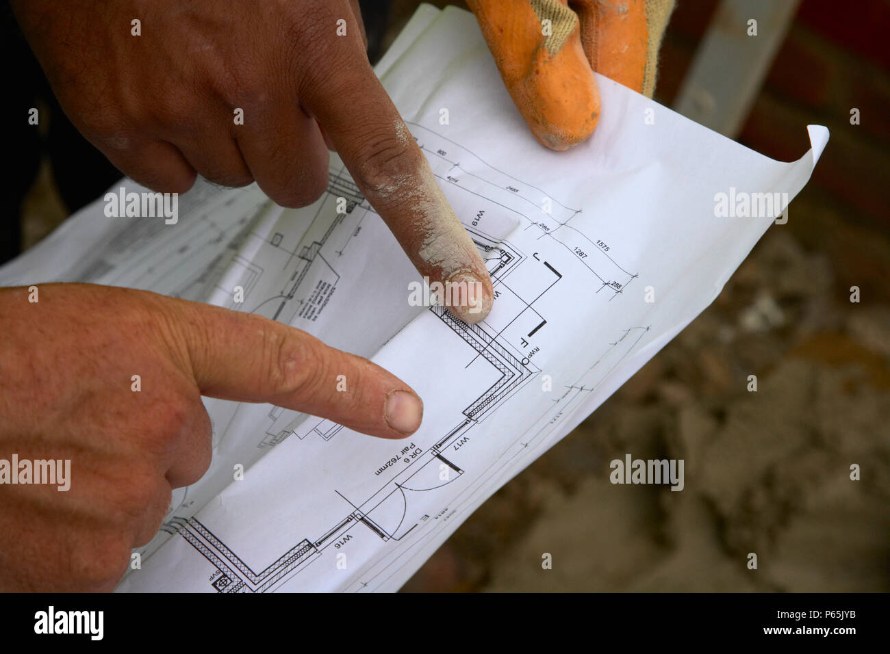 Building workers looking at plans Stock Photo - Alamy