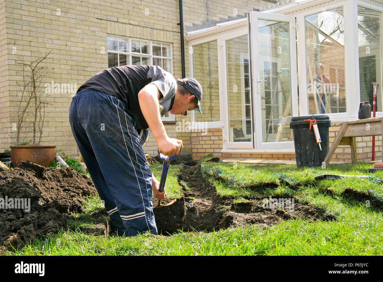 Builder digging a trench in a garden with a spade Stock Photo - Alamy