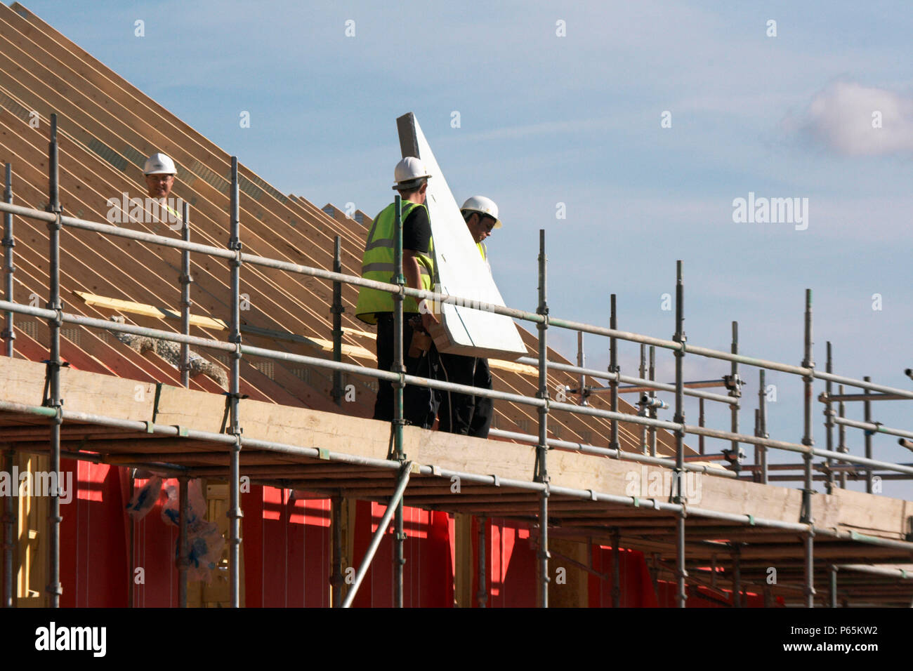 Construction workers carrying pre-fabricated section at new housing ...