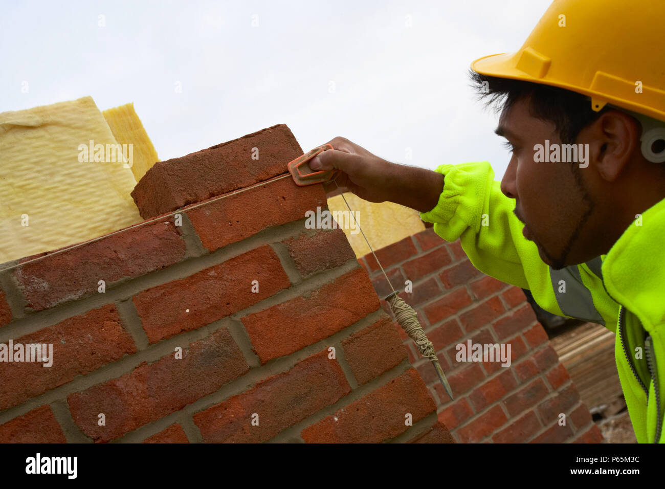 Bricklayer checking level with string line on a house building site ...