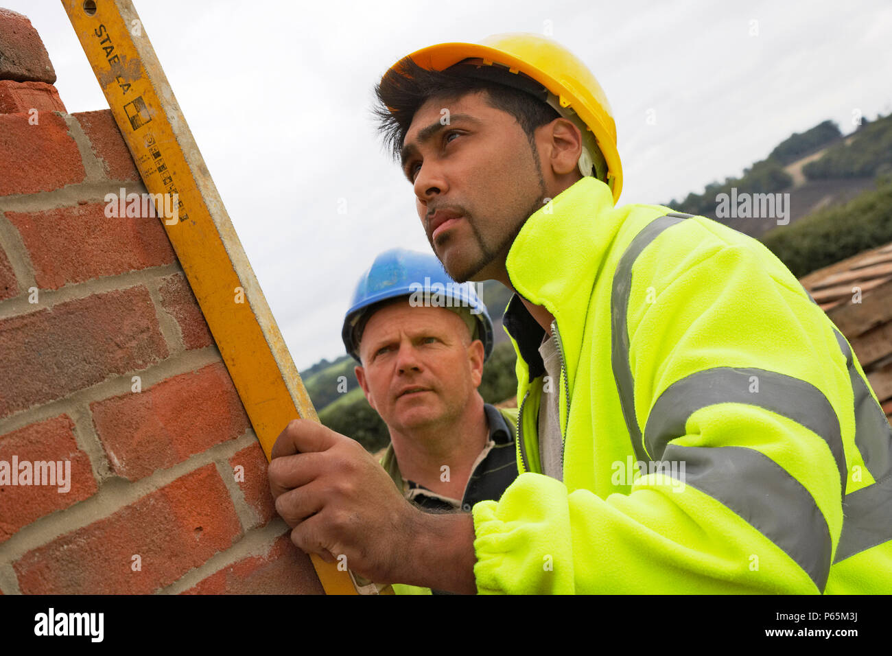 Bricklayer and foreman checking levels on a house building site ...