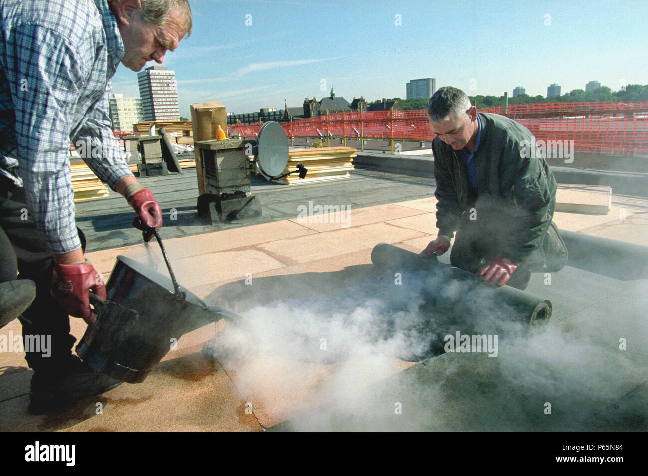 Bituminous Roofing. Pouring Bitumen on a flat roof of a Council Estate ...