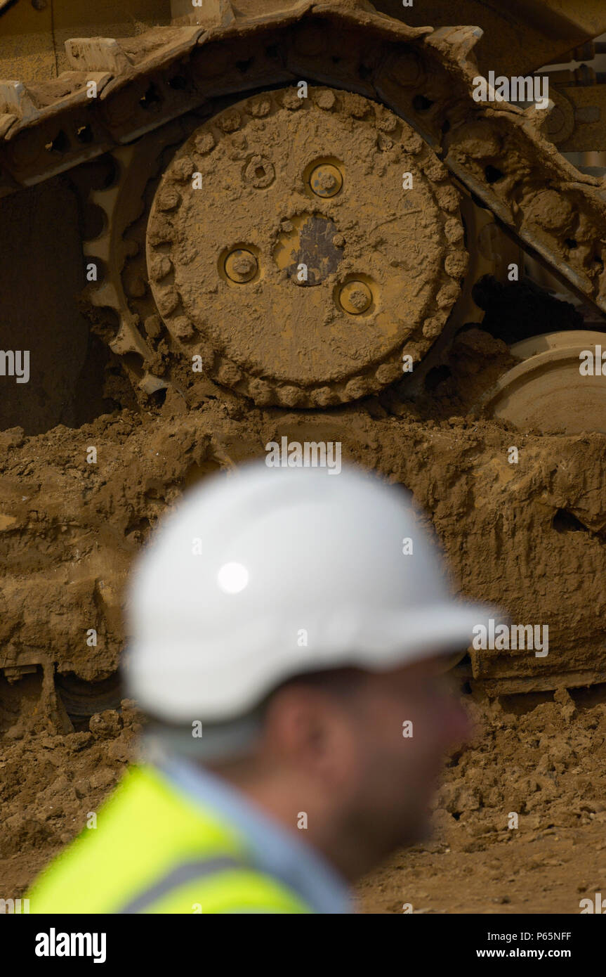 Construction Foreman walking with detail of tracked machinery Stock ...