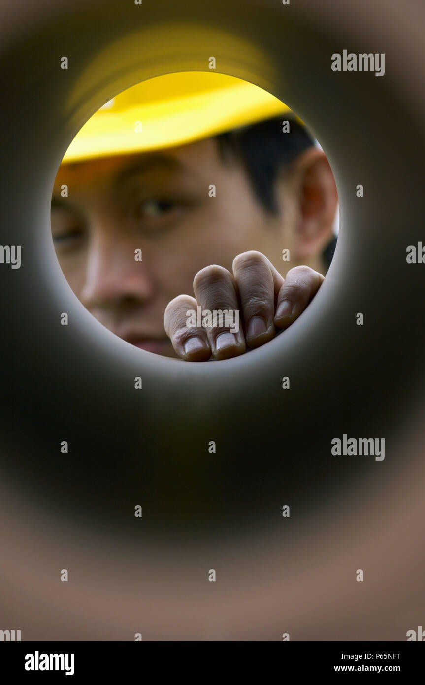 Construction worker looking into a pipe Stock Photo - Alamy