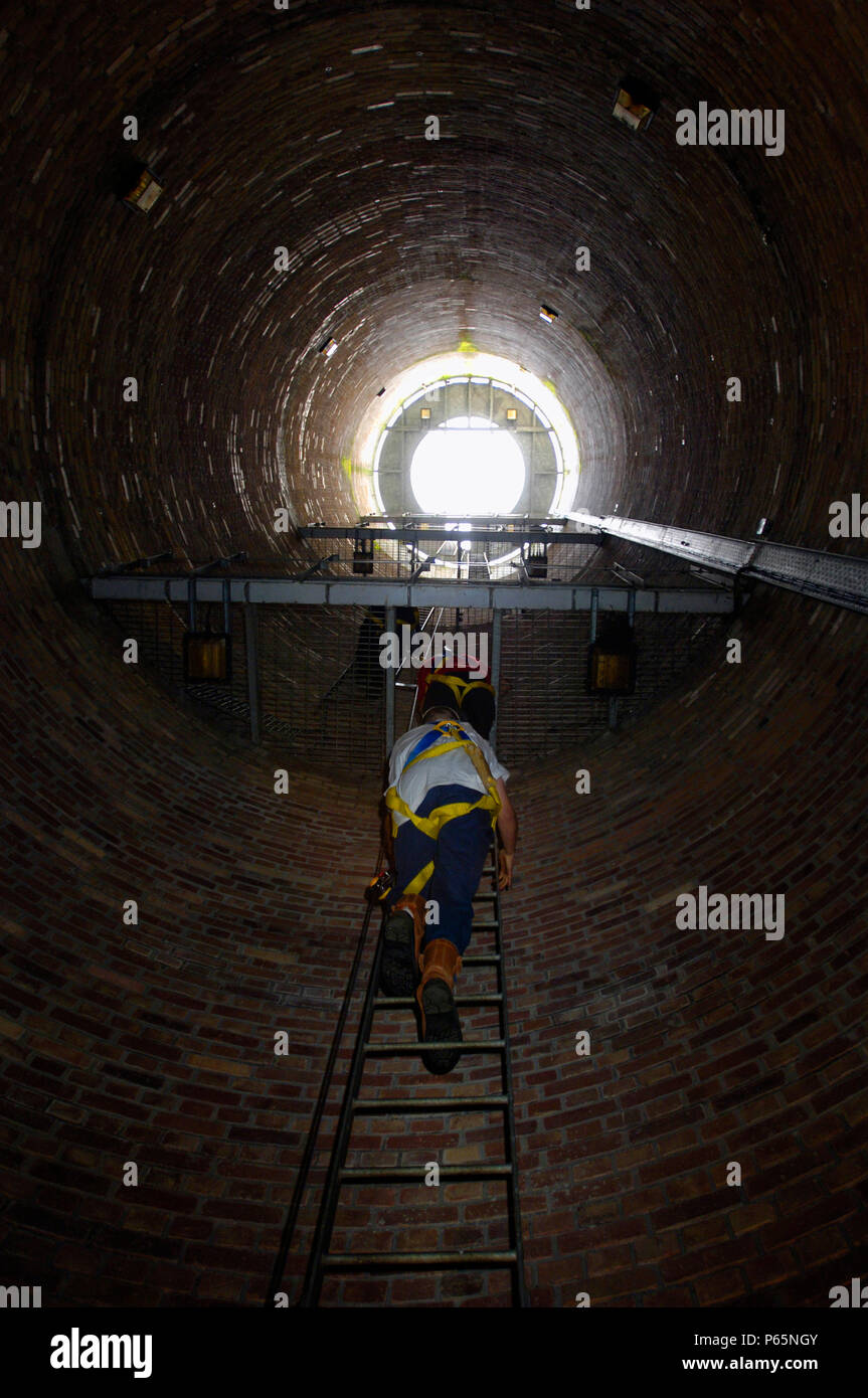 Scaffolding operator climbing a ladder inside a chimney tower Stock ...