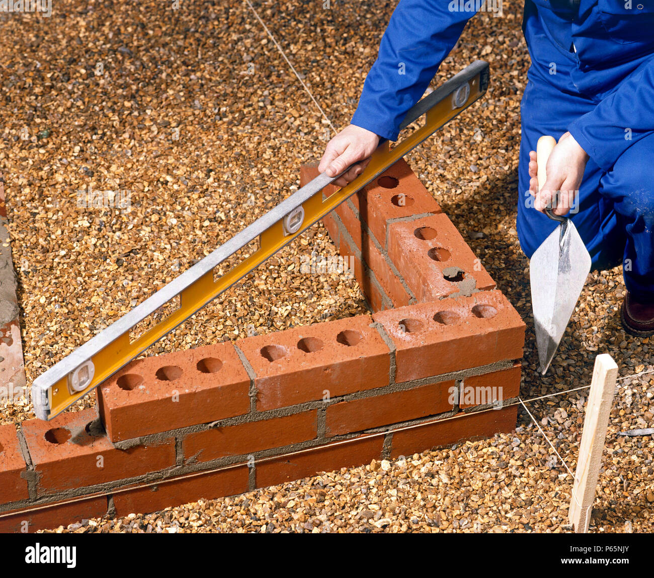 Bricklayer checking level on a Brickwall Stock Photo - Alamy