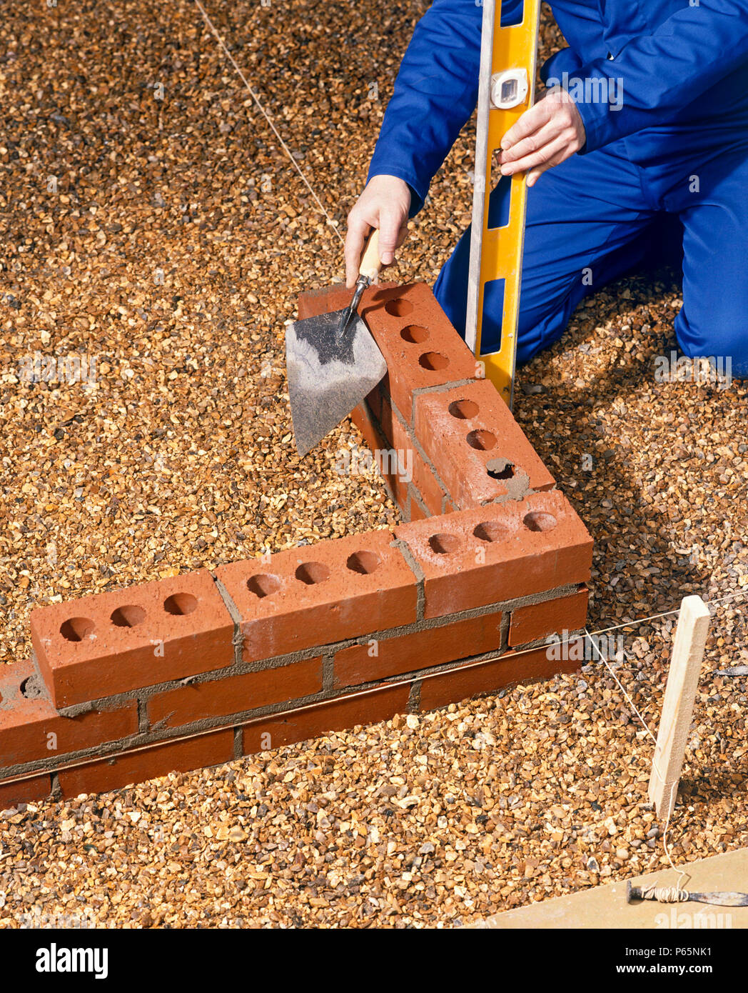 Bricklayer checking level on a Brickwall Stock Photo - Alamy