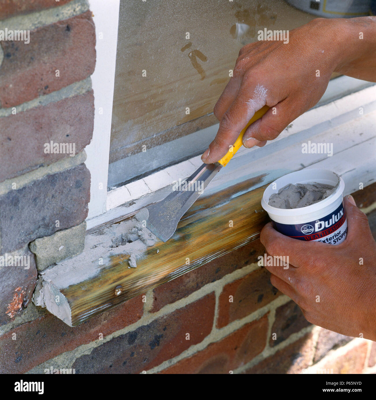 Repairing a damaged window. Applying wood filler Stock Photo - Alamy