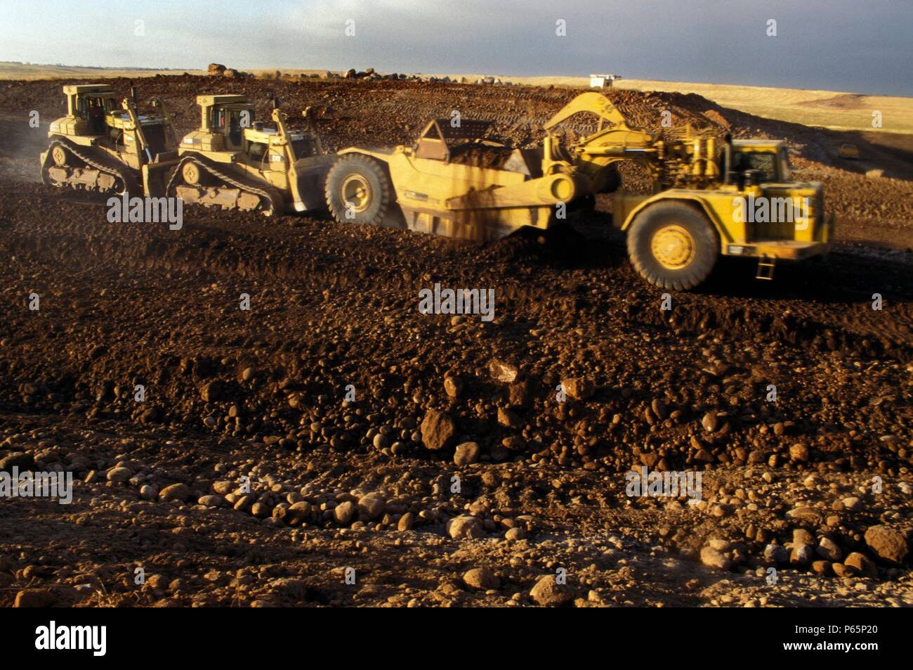 Two bulldozers pushing scraper to load with dirt Stock Photo - Alamy