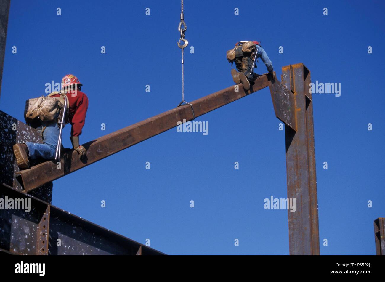 Ironworker connectors installing beam supported by tower crane cable ...