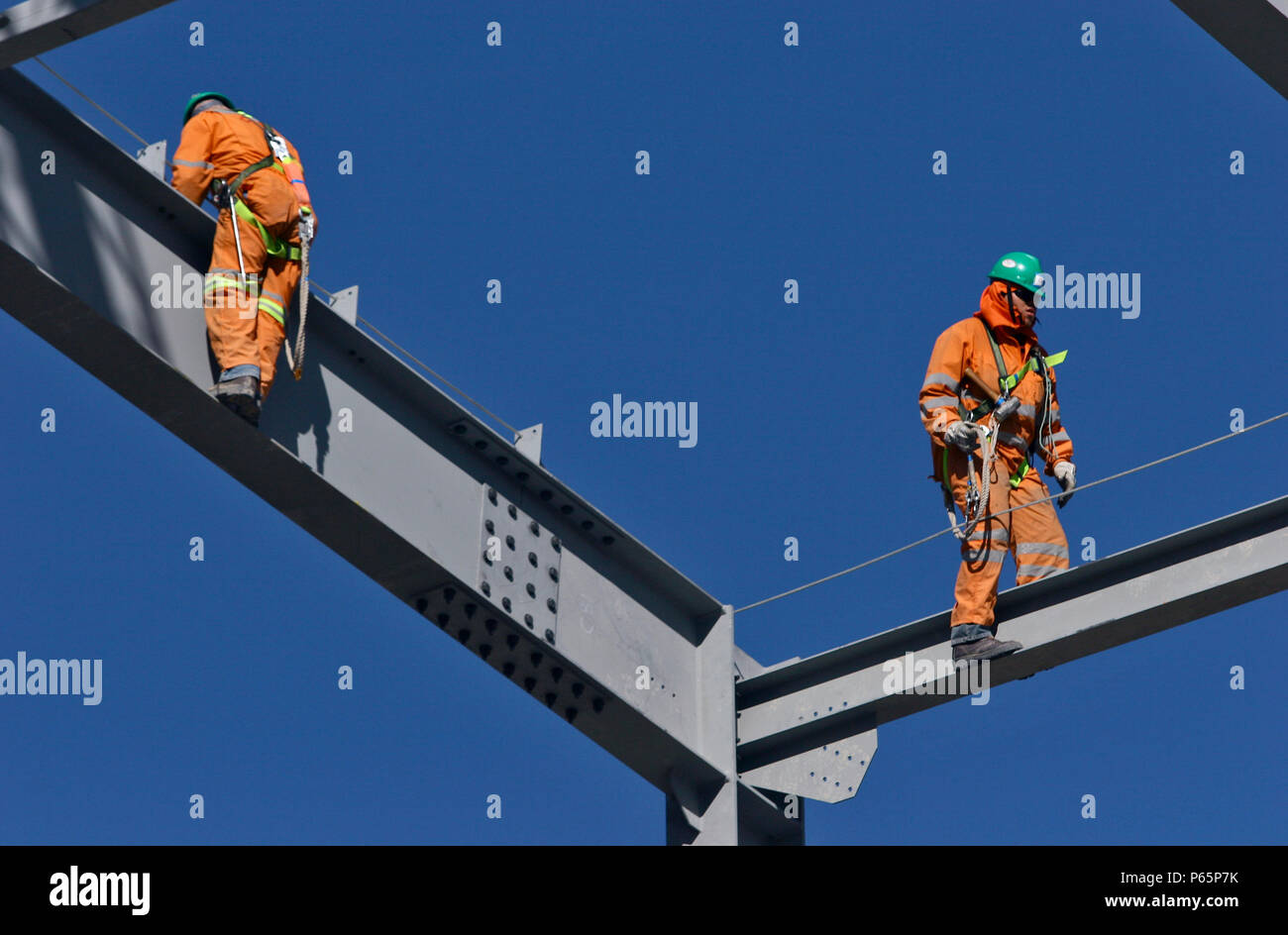 Steel workers walking on steel beams with safety attachment Stock Photo ...