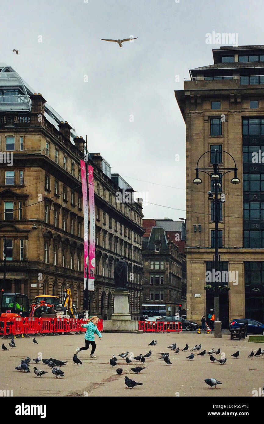 A girl chasing pigeons in the city square, George Square, Glasgow ...