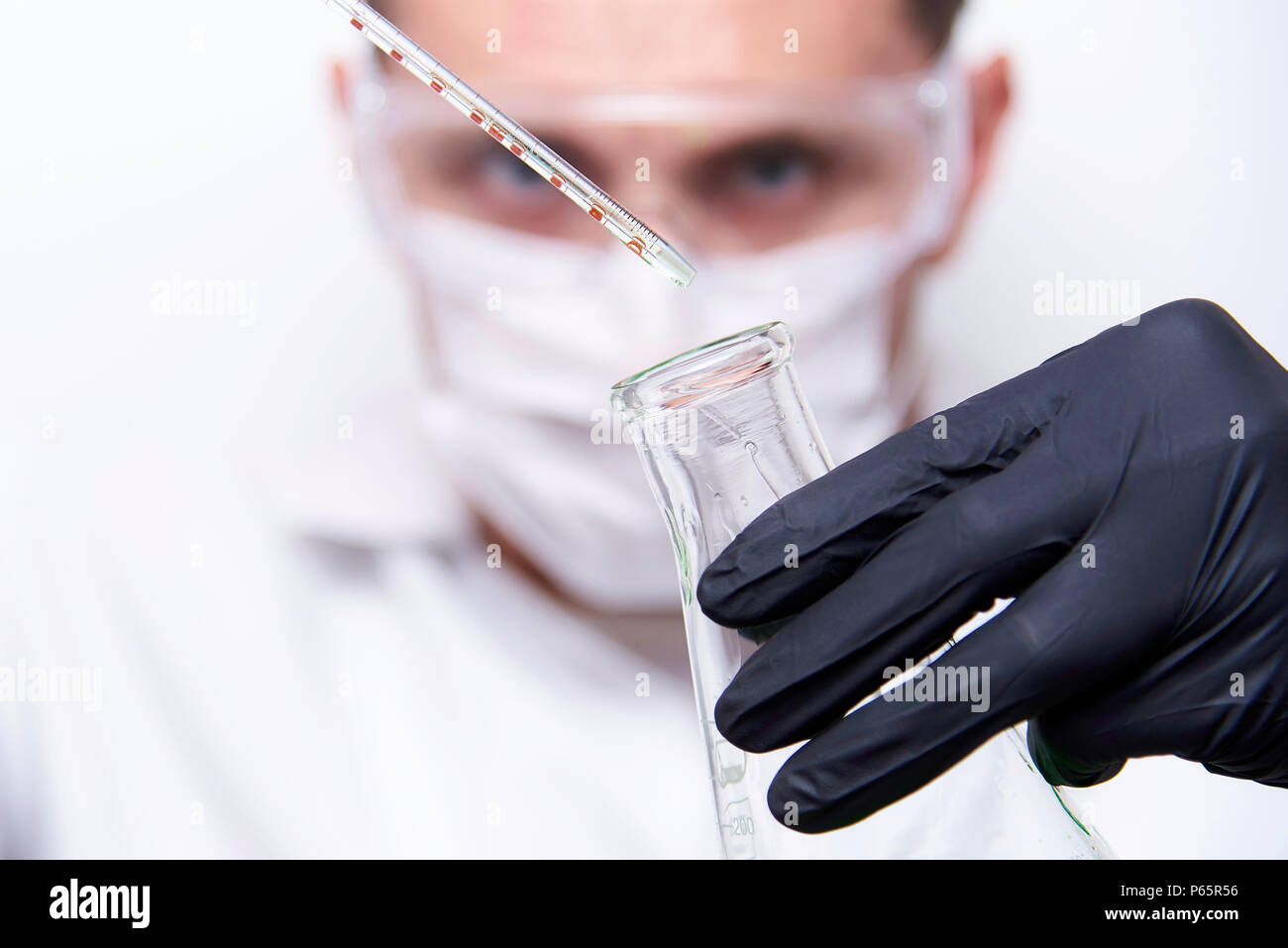 A test tube and a glass bulb in the hands of a scientist, wearing ...