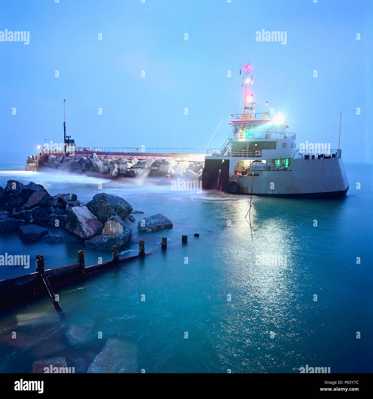 Placing rocks to form sea defences using side tipping barge Stock Photo ...