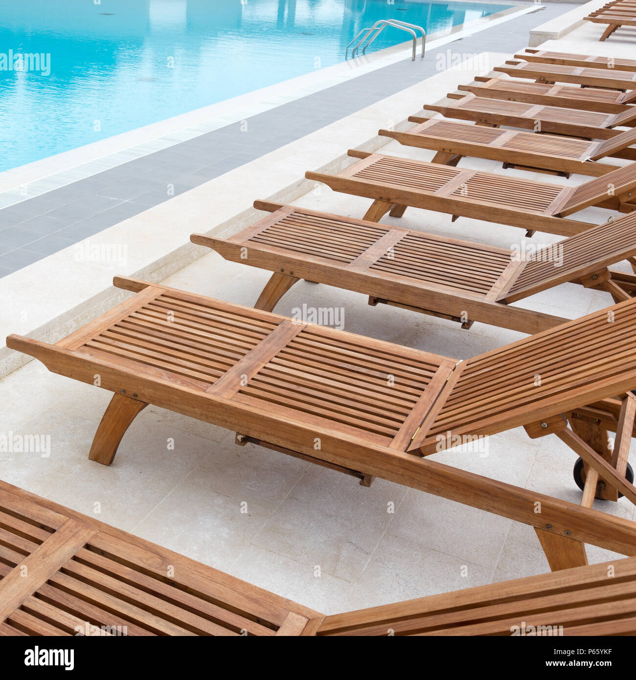 Luxury swimming pool with wooden deck chairs Stock Photo - Alamy