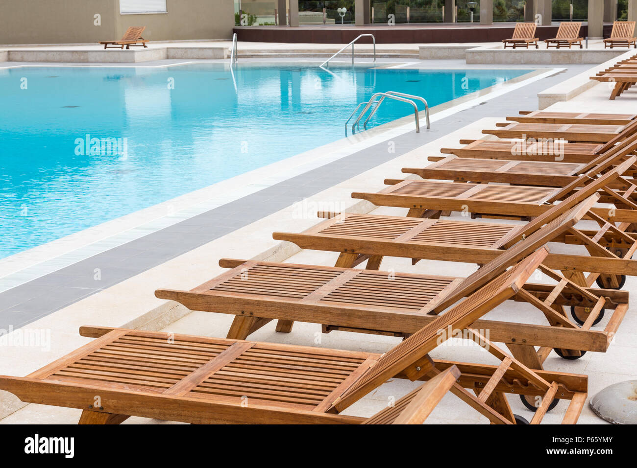 Luxury swimming pool with wooden deck chairs Stock Photo - Alamy