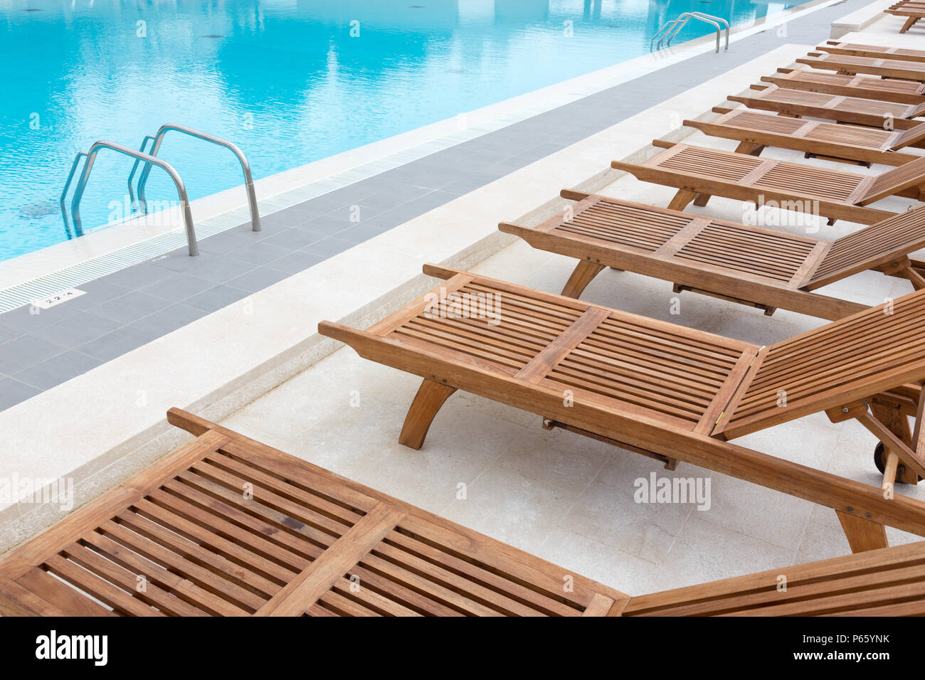 Luxury swimming pool with wooden deck chairs Stock Photo - Alamy