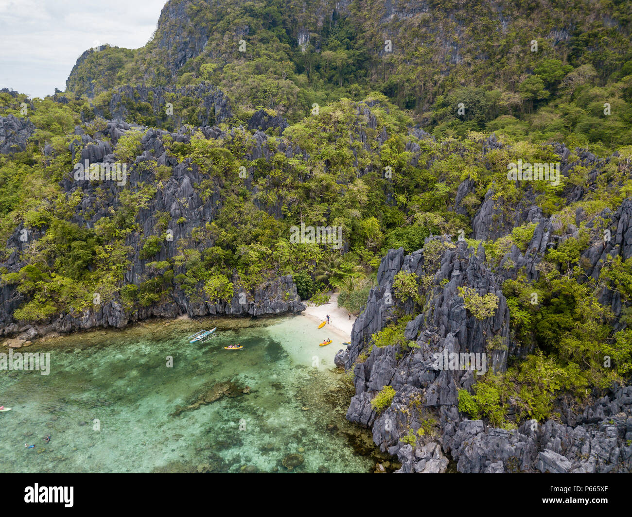 Aerial drone view of boats around a tiny sandy beach on a tropical ...