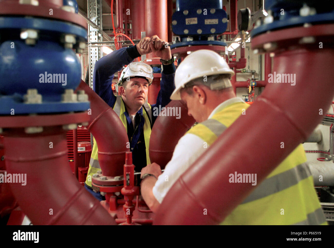 Two workers working as a team. Tightening valves using a spanner Stock ...