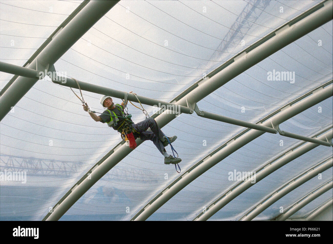 Construction worker suspended from roof top securing canopy Stock Photo ...