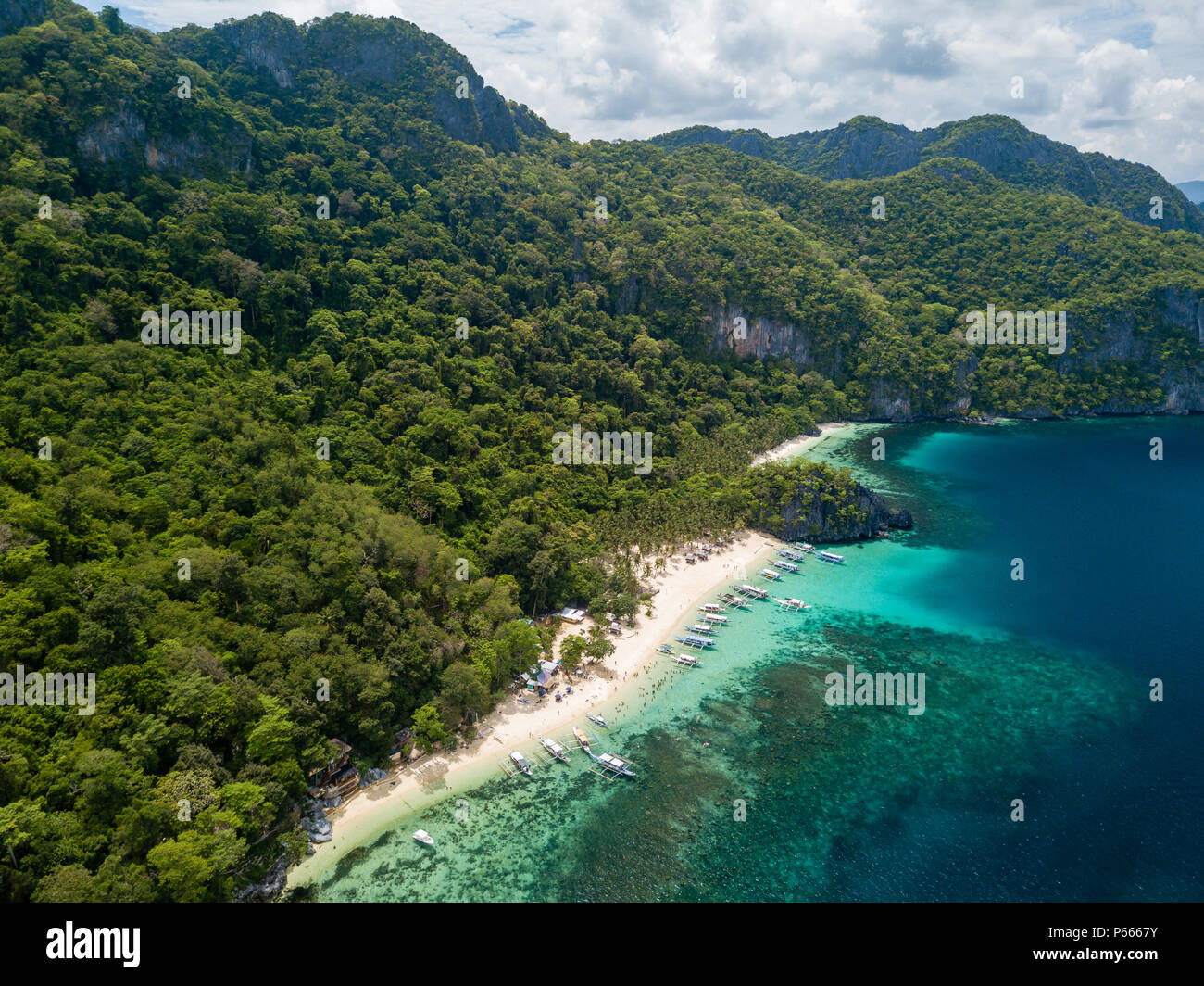 Aerial drone view of a small, tropical sandy beach and tourist boats ...