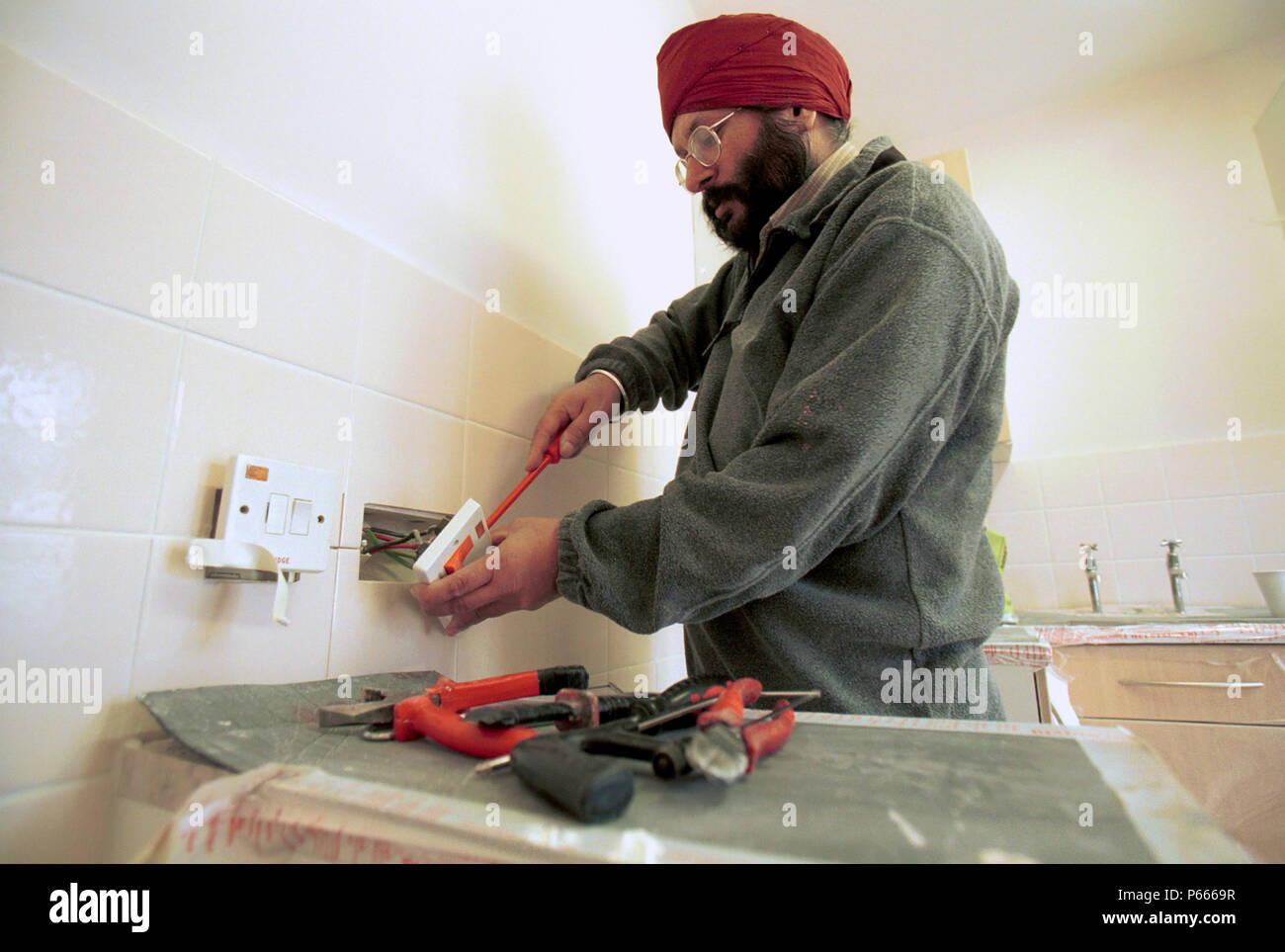 Electrician wiring a socket. Council Houses refurbishment, London Stock ...