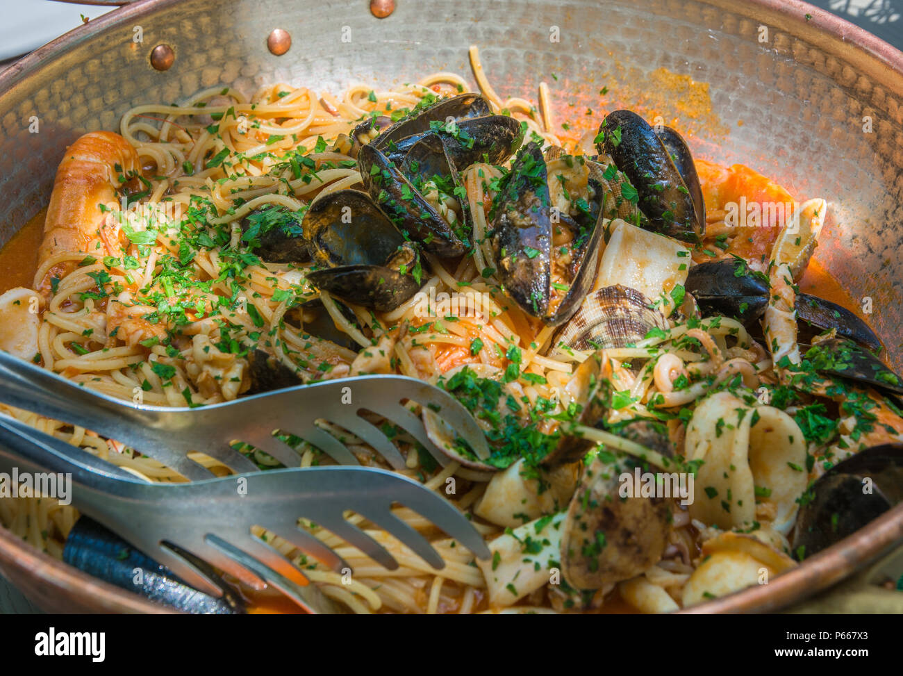 Spaghetti with mussels and cuttlefish just served in the copper pot ...
