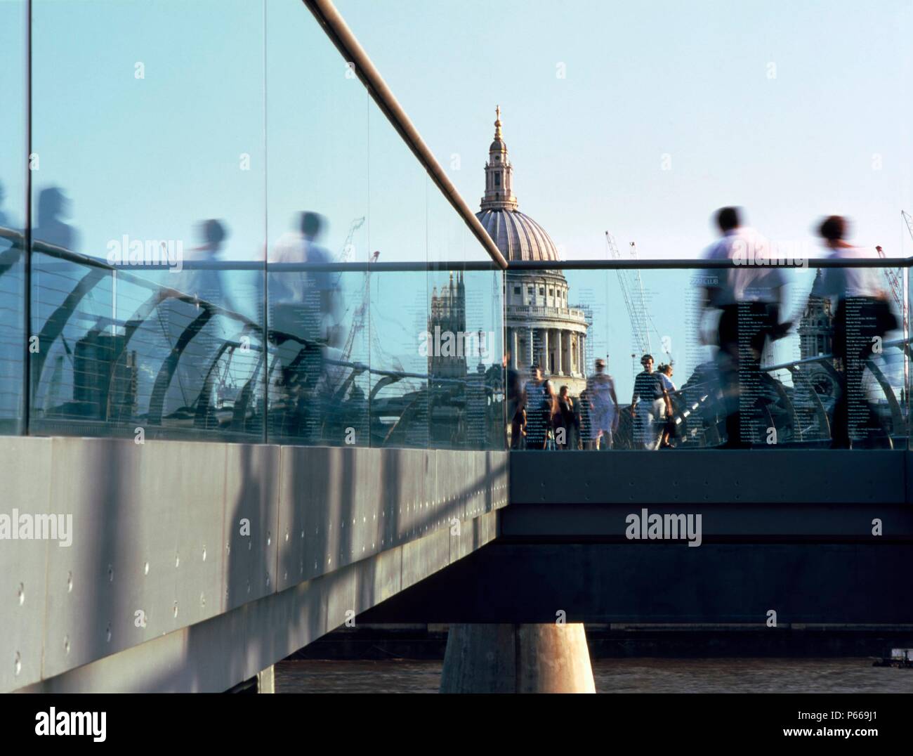 People crossing the Millennium footbridge with St Pauls Cathedral in ...