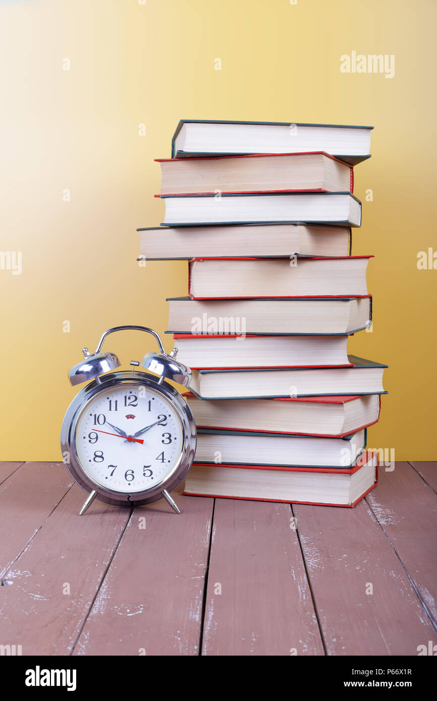 Science and education - alarm clock and high pile group of red books on ...