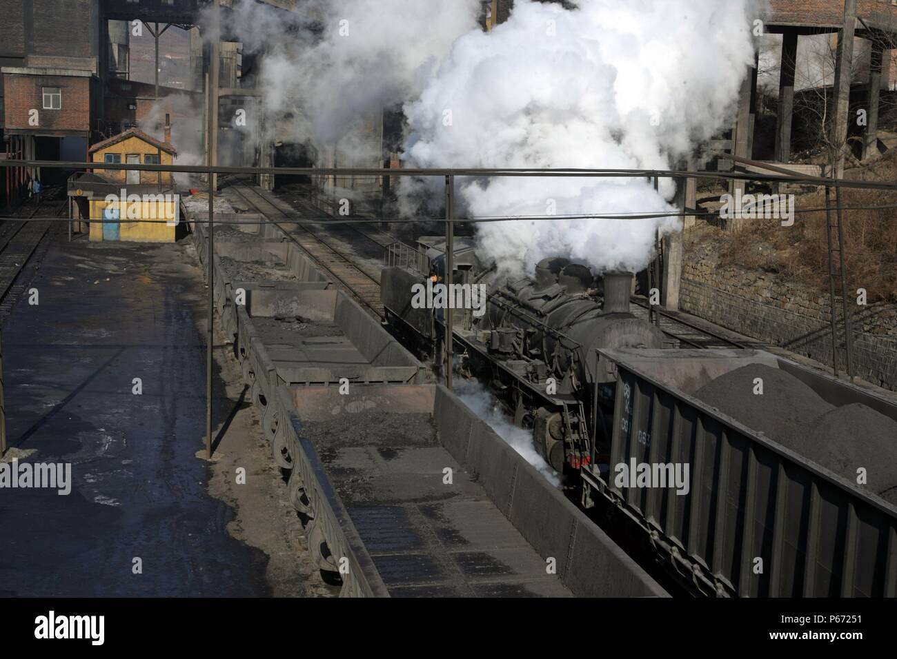 A rake of spoil wagons wait to be loaded behind a Chinese SY class ...